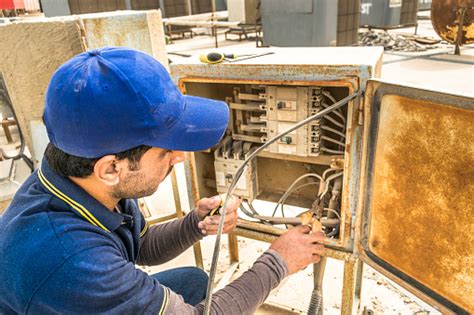 전문 전기 기술자는 지붕 상단에 무거운 의무에 어 컨디셔너 단위의 전기 공급의 중요 한 문제를 해결 하 고 파란색 유니폼을 입고 도시는 배경에 Stem 주제에 대한 스톡