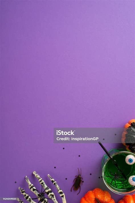 할로윈 개념 녹색 음료 플로팅 아이볼 펀치 밀짚 거미 호박 해골 손 바퀴벌레와 카피 스페이스가있는 고립 된 보라색 배경에 색종이가있는 유리의 상단보기 수직 사진 0명에 대한