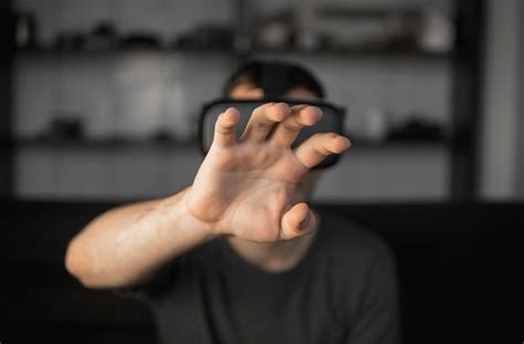 젊은 수염 남자는 소파에 앉아 사무실에서 가상 현실의 헤드셋을 착용 하 고 가상 세계에서 볼 무언가를 만지지 하려고 합니다