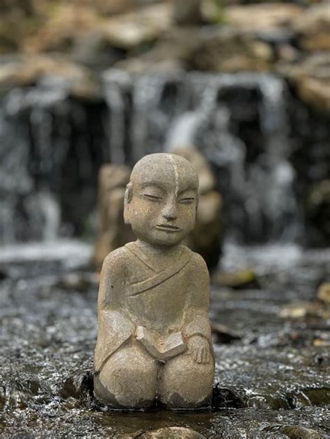 A Stone Statue Of A Buddha Sitting In Front Of A Waterfall · Free Stock