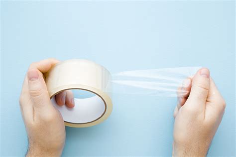 남자 손 스트레칭 투명 스카치 밝은 파스텔 파란색 배경입니다 근접 촬영 평면도 접착 테이프에 대한 스톡 사진 및 기타 이미지