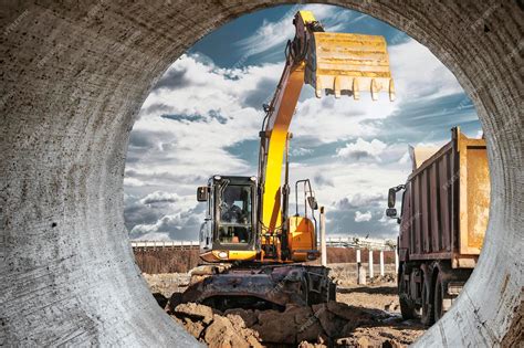 Premium Photo A Wheeled Excavator Loads A Dump Truck With Soil And