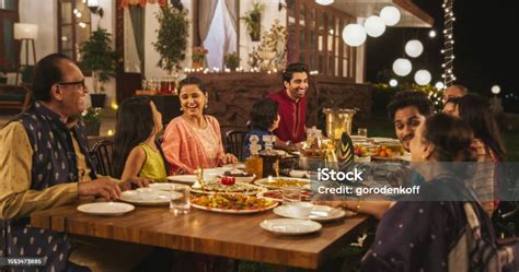 밤에는 멋진 집 정원에서 야외에서 함께 식사를 하는 행복한 대인도 가족 맛있는 음식을 먹으며 웃고 재미있는 이야기와 추억을 나누는 가족들 가족에 대한 스톡 사진 및 기타