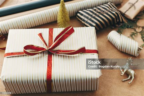 줄무늬 황금 종이와 빨간 활 가위 선물 황금 나무 나무 테이블에 사슴세련된 크리스마스 선물 상자 포장 크리스마스 선물 컨셉 즐거운 성탄절 가위에 대한 스톡 사진 및 기타