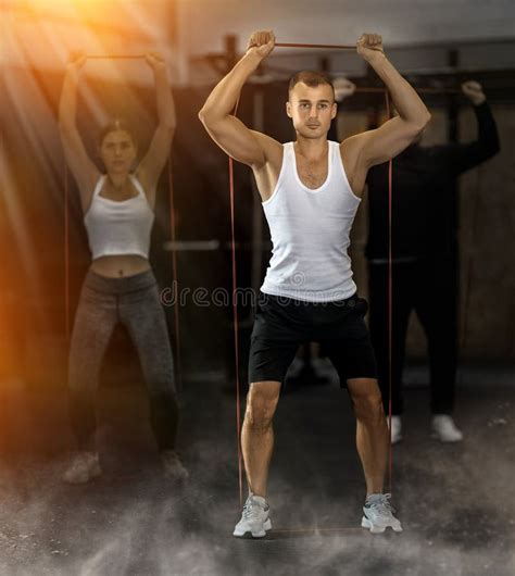 Determined Young Guy Working Out With Resistance Band In Gym Stock
