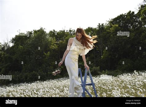 A Beautiful Red Haired Girl In A Long White Dress Poses In The Middle