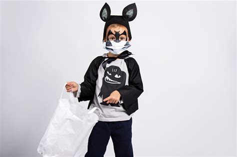 할로윈 의상과 얼굴 마스크에서 아이 트릭 또는 치료 코로나바이러스 전염병에 사탕 양동이와 드레스에 소년 가을 휴가 재미 충분한