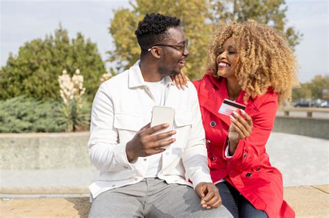 신용 카드와 스마트 폰을 공유 할 때 야외에 앉아있는 남성과 여성 25 29세에 대한 스톡 사진 및 기타 이미지 25 29세 2명 30 34세 Istock
