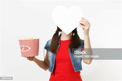 영화 영화를 보고 팝콘의 물통을 들고와 복사 공간 흰색 배경에 고립 된 하얀 마음으로 얼굴을 덮고 캐주얼 옷에 젊은 갈색 머리 여자의 초상화 극장에서의 감정