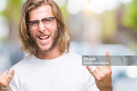 손으로 바위 상징 하 고 미친 식 소리 고립 된 배경 위에 안경을 쓰고 긴 머리를 가진 젊은 잘생긴 남자 음악 스타입니다 무거운 개념입니다 개념에 대한 스톡 사진 및 기타