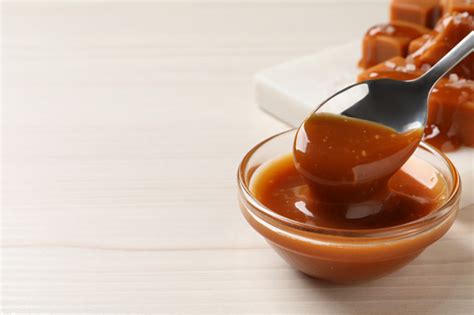 하얀 나무 테이블에서 유리 그릇에서 숟가락으로 맛있는 소금에 절인 캐러멜을 가져 와서 클로즈업하십시오 텍스트를 위한 공간 0명에