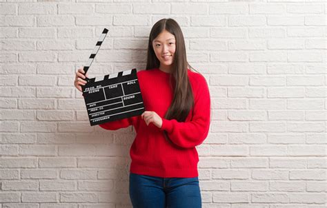 서 치아를 보여주는 자신감 미소로 웃 고 행복 한 얼굴로 판자를 들고 흰 벽돌 벽을 통해 젊은 중국 여자 아시아에 대한 스톡