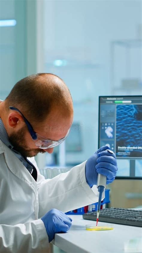 Man Scientist Using Micropipette For Filling Test Tubes In Modern Equipped Laboratory Stock