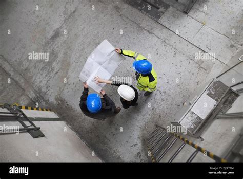 Top View Of Engineer And Industrial Worker In Uniform Shaking Hands In Large Metal Factory Hall