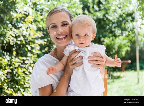 Portrait Of Happy Mother Holding Her Baby Girl Outdoors Stock Photo Alamy