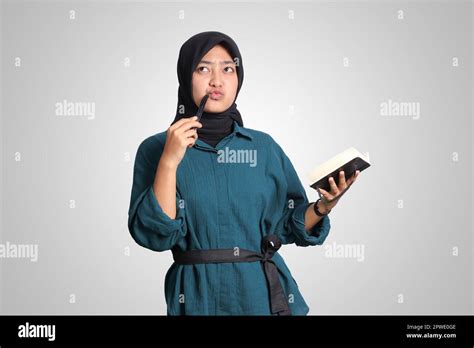 Portrait Of Excited Asian Muslim Woman With Hijab Writing On Note Book