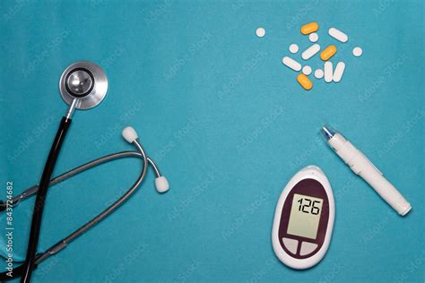 청녹색 배경에 있는 청진기 그리고 혈당 측정기와 혈당 측정 차트와 알약 Foto De Stock Adobe Stock
