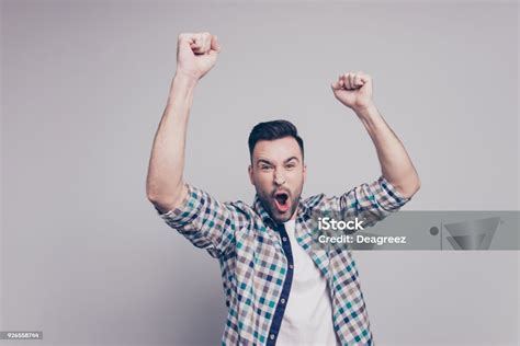 캐주얼 체크 무늬 셔츠 제기 팔 카메라 좋아하는 스포츠 팀의 승리를 축 하 소리 비명 회색 배경 오픈 입으로 소리에 다름 Brunet 사람을 깜짝 놀라게 대학교에 대한 스톡