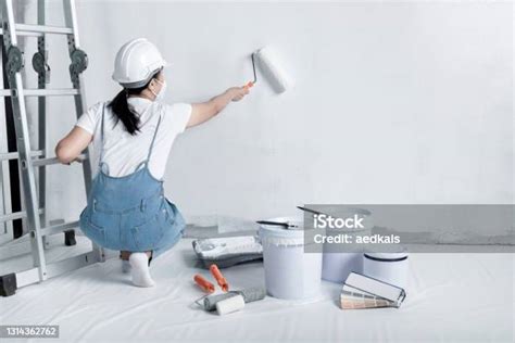 소녀는 롤러와 흰색 벽을 페인트 내부의 수리 빈 방에 벽을 그리는 젊은 여성 데코레이터 개념 빌더 또는 화가가 빈 방에 페인트