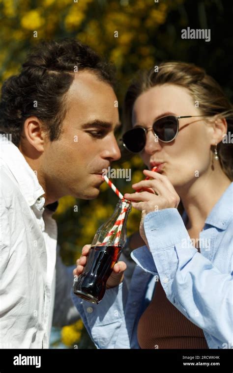 Young Happy Couple Outdoors Drinking Cold Drink From Glass Bottle With