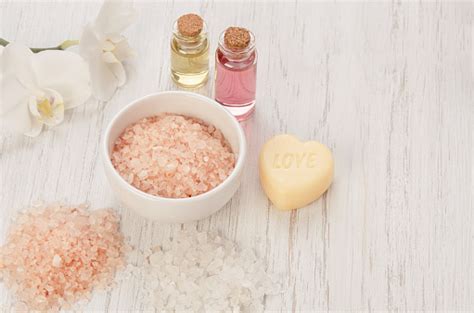 Spa 바디 케어 컨셉 목욕 소금 에센셜 오일 또는 물을 곁들인 유리 병 흰색 나무 배경의 난초 꽃 건강관리와 의술에 대한 스톡