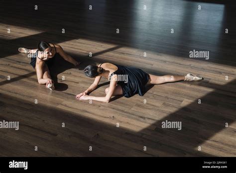 Couple Of Young Woman Dancers Doing A Stretching Routine On The Floor