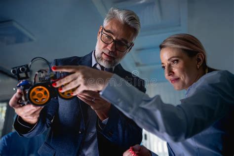 Two Robotics Engineers Assembling Robotic Car Concept Of Modern Technology In Industries