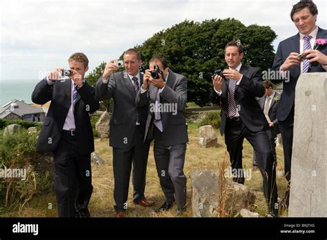 Five Men Wearing Suits Guests At Wedding Taking Photographs On Their