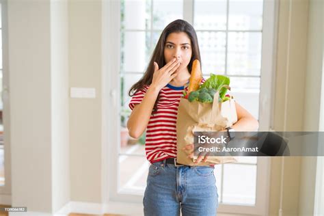 실수 두려움의 표현 침묵에 무서 워 비밀 개념의 수치와 손을 충격으로 식료품 커버 입으로 가득 종이 가방을 들고 젊은 여자 가득 찬에 대한 스톡 사진 및 기타 이미지