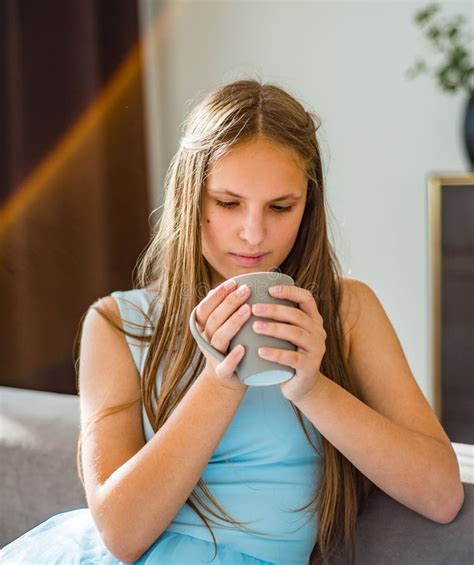 Young Teenager Brunette Girl With Long Hair Sitting On Sofa With Cup At