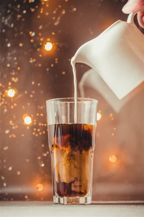 Pouring Cream From White Creamer Into Hot Coffee In A Glass Coffee