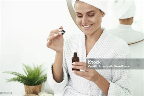 보습 세럼을 사용하여 눈 덮인 흰색 미소와 함께 Vitiligo와 사랑스러운 소녀 미소 손의 배경에 파이펫에서 드롭퍼의 클로즈업