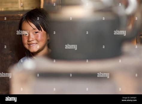 A Young Bhutanese Girl Peeks From Behind A Stove And Teapot Bhutan