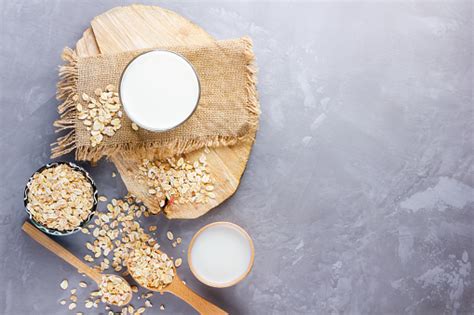 귀리 우유 나무 스탠드에 유기농 귀리 우유 귀리 플레이크가 있는 비건 비유제품 유기농 음료 시멘트 배경에 대체 우유 폐기물 제로 0명에 대한 스톡 사진 및 기타 이미지