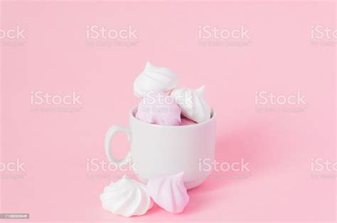분홍색 배경에 작은 도자기 커피 컵에 흰색과 분홍색 트위스트 머 랭 설탕을 휘 핑 하 고 달걀 흰 자를 구워 만든 프렌치 디저트