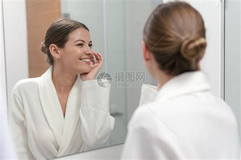 穿着白色浴袍的年轻成人和迷人的女人站在带镜子的明亮浴室里高清图片下载 正版图片502982581 摄图网