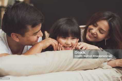 젊은 어머니 아버지와 딸 베개와 침대에서 뱃속에 거짓말과 함께 즐기는 집에서 웃는 행복 한 가족 가족에 대한 스톡 사진 및 기타