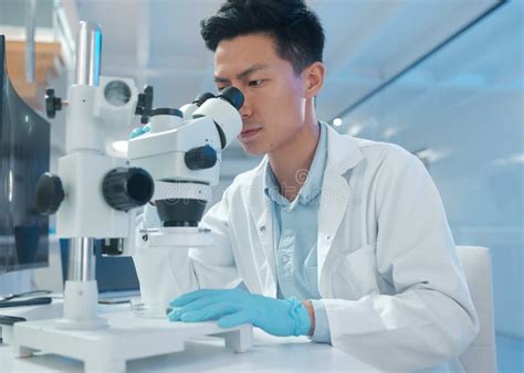 Finding A Needle In A Haystack A Young Male Technician Analysing Samples Using A Microscope