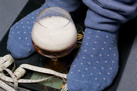 한 남자가 바닥 비늘 위에 서 있었다 그의 앞에는 맥주 한 잔과 측정 테이프가 있습니다 크래커와 칩이있는 컵 근처 세계 아니