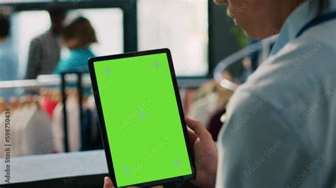 Asian store worker holding chroma key green screen mock up tablet ...