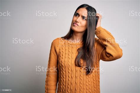 고립 된 흰색 배경에 캐주얼 스웨터를 입고 젊은 아름다운 갈색 머리 여자는 혼란에 대한 질문에 대해 궁금 의심의 여지가 머리에