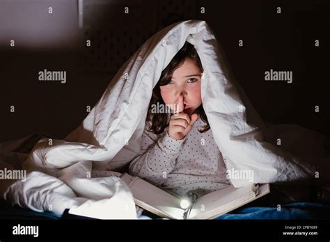 Cheerful Preteen Girl In White Pajamas Sitting On Bed With Crossed Legs