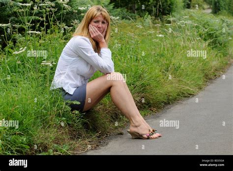 Reife Frau Trägt Ein Weißes Hemd Und Rock Sitzt Am Straßenrand Stockfotografie Alamy