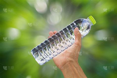 手握饮用水瓶上模糊变焦焦背景