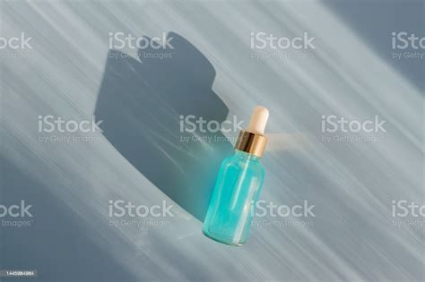 화장품 스파 의료 스킨케어 그림자가 있는 파란색 배경에 콜라겐이 있는 유리 혈청 병 해양 원료를 사용한 안티에이징 케어를 위한