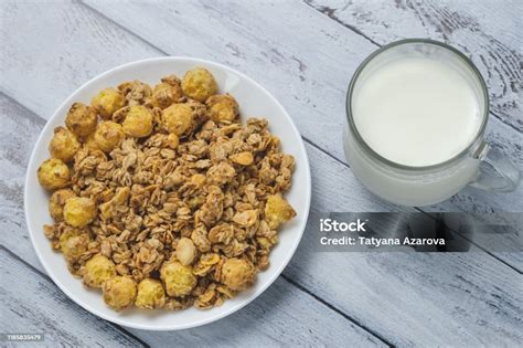 회색 나무 보드에 우유 한 잔 과 그래놀라의 흰색 접시 시리얼건조와 견과류를 섞어 우유와 함께 아침 식사 회색 나무 테이블에 흰색 접시에 압연 귀리와 우유의 유리 컵 0명에