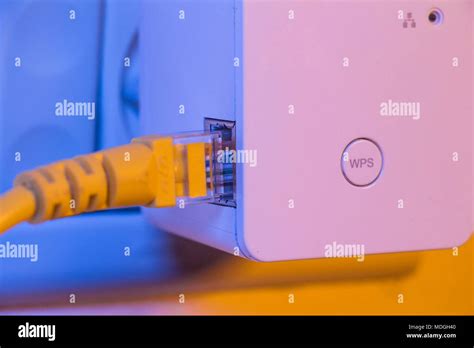 WiFi Extender In Electrical Socket On The Wall With Ethernet Cable Plugged In The Device Is In