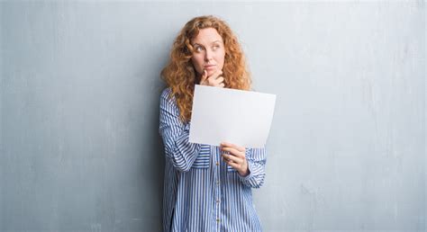 젊은 빨강 머리 여자 회색 그런 지 이상 벽 질문 매우 혼란 스 러 워 아이디어에 대해 빈 종이 시트 심각한 얼굴 생각 들고