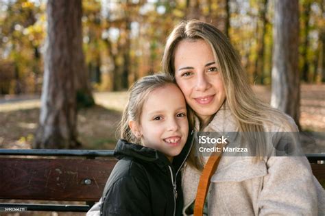 Happy Aunt And Her Niece Are Hugging In An Autumn Park And Looking At