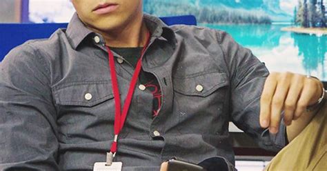 A Dark Haired Young Man Wearing A Blue Shirt Khaki Pants And A Red